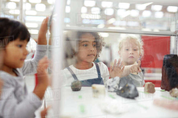Curious kids looking at rocks in display case in science center ...