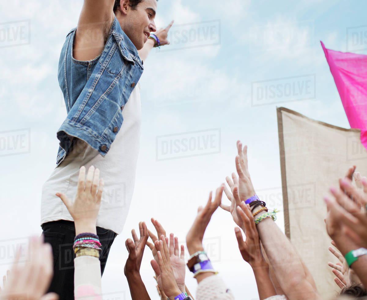 Performer standing above cheering crowd at music festival - Royalty ...