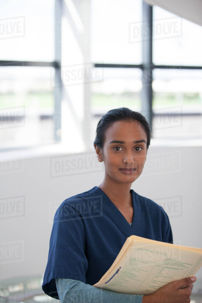 Nurse carrying folder in hospital hallway - Stock Photo - Dissolve
