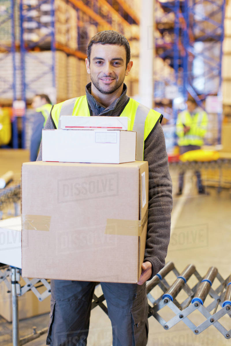 Worker carrying boxes in warehouse - Stock Photo - Dissolve