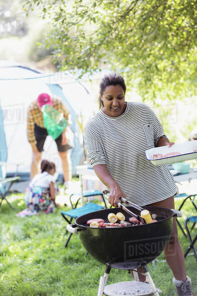 Woman barbecuing at campsite - Royalty-free Stock Photo | Dissolve