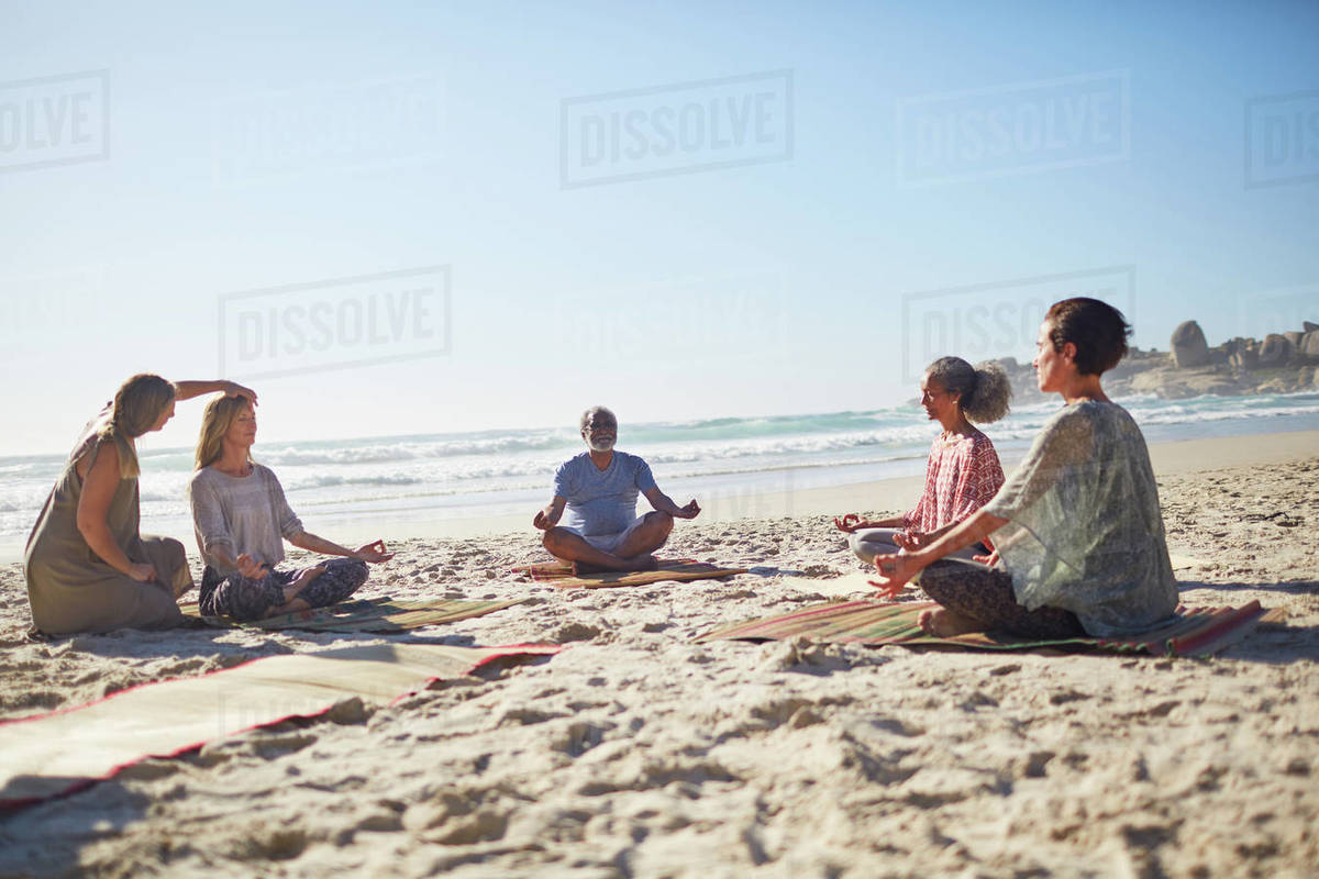 Group meditating on sunny beach during yoga retreat - Stock Photo ...