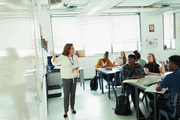 High school students watching teacher leading lesson at whiteboard in ...