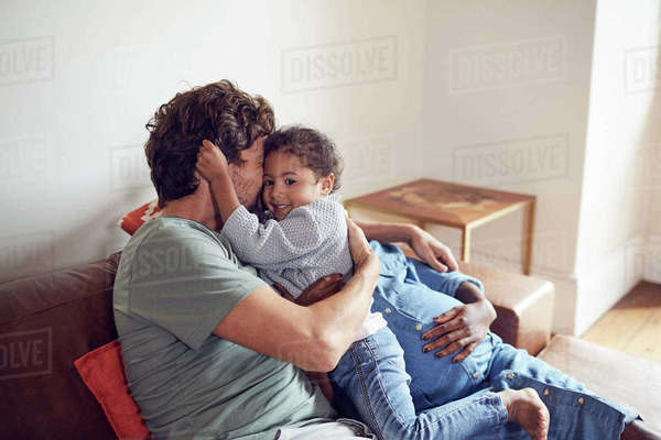 Affectionate young pregnant family cuddling on sofa - Royalty-free ...