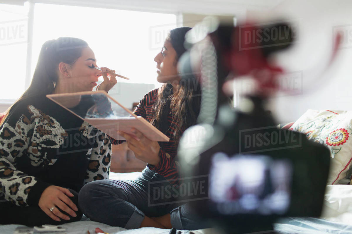 Teenage girls vlogging, demonstrating makeup application in bedroom ...