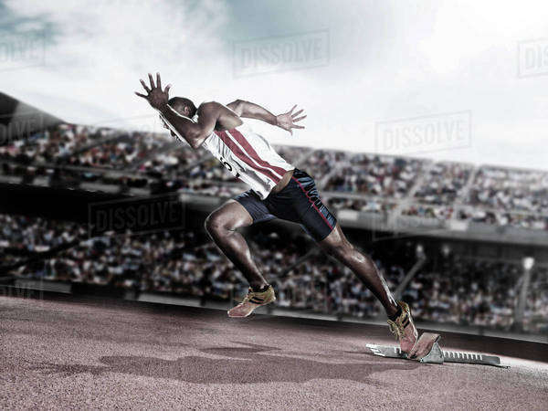Runner taking off from starting block on track - Stock Photo - Dissolve