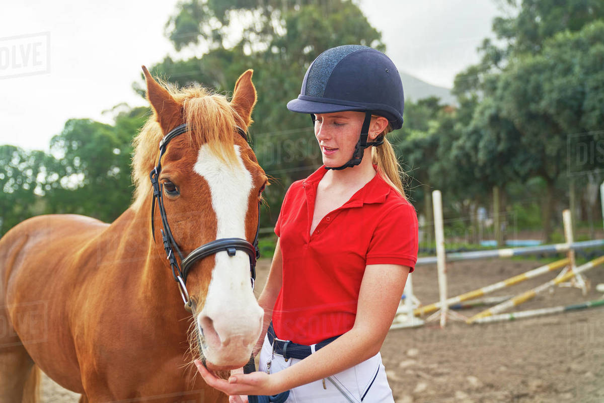 Teenage girl in equestrian helmet with horse in paddock - Royalty-free ...