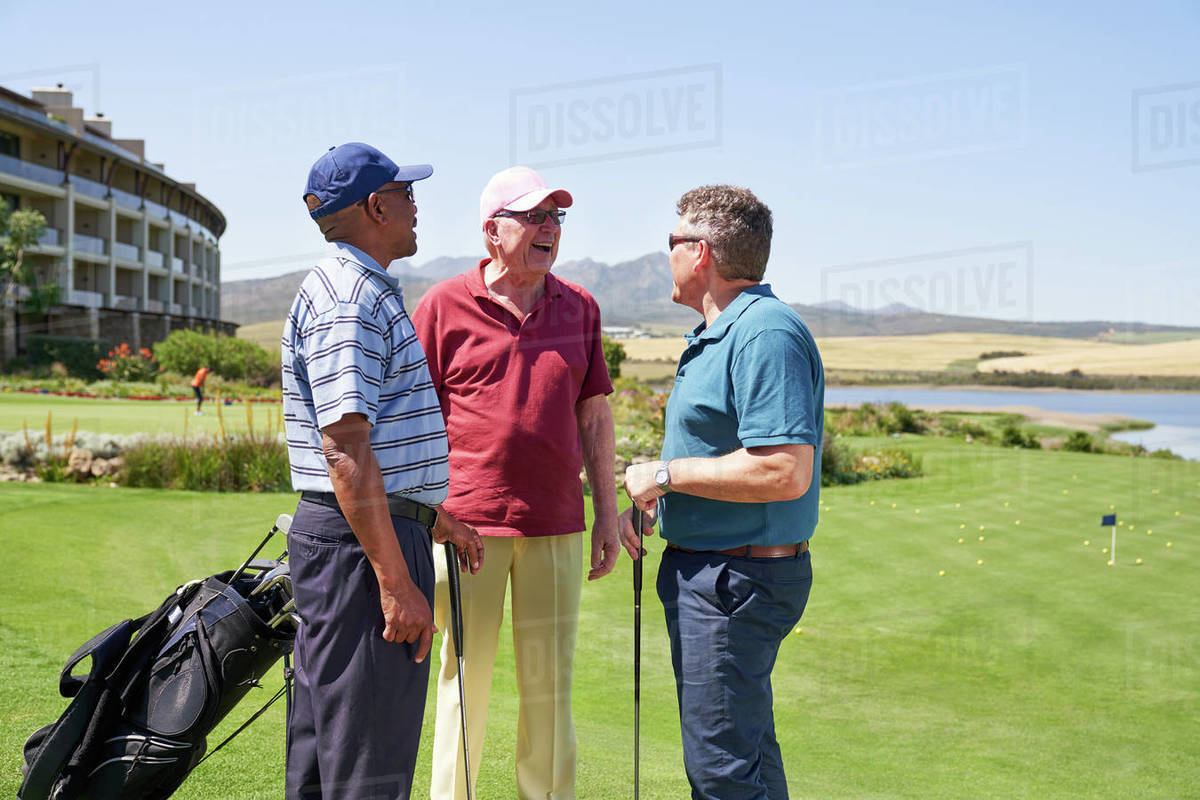 Happy male golfer friends talking on sunny golf course - Stock Photo ...
