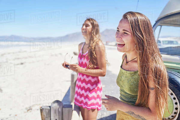 Happy young women friends laughing on sunny beach - Stock Photo - Dissolve