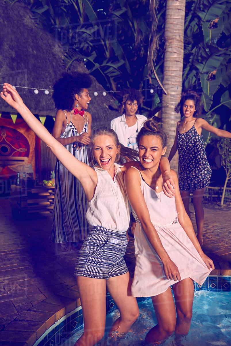 Portrait exuberant young women friends partying, dancing and wading at ...