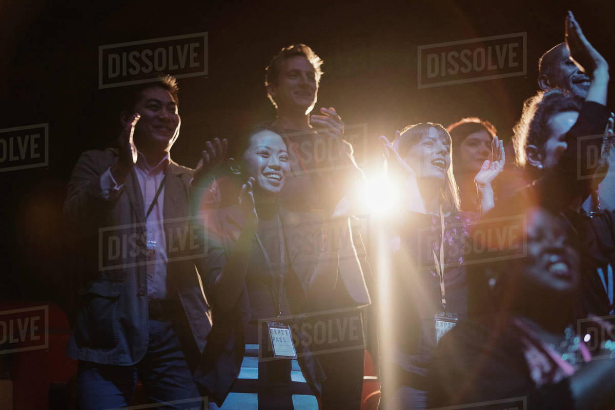 Happy audience clapping in dark room - Royalty-free Stock Photo | Dissolve
