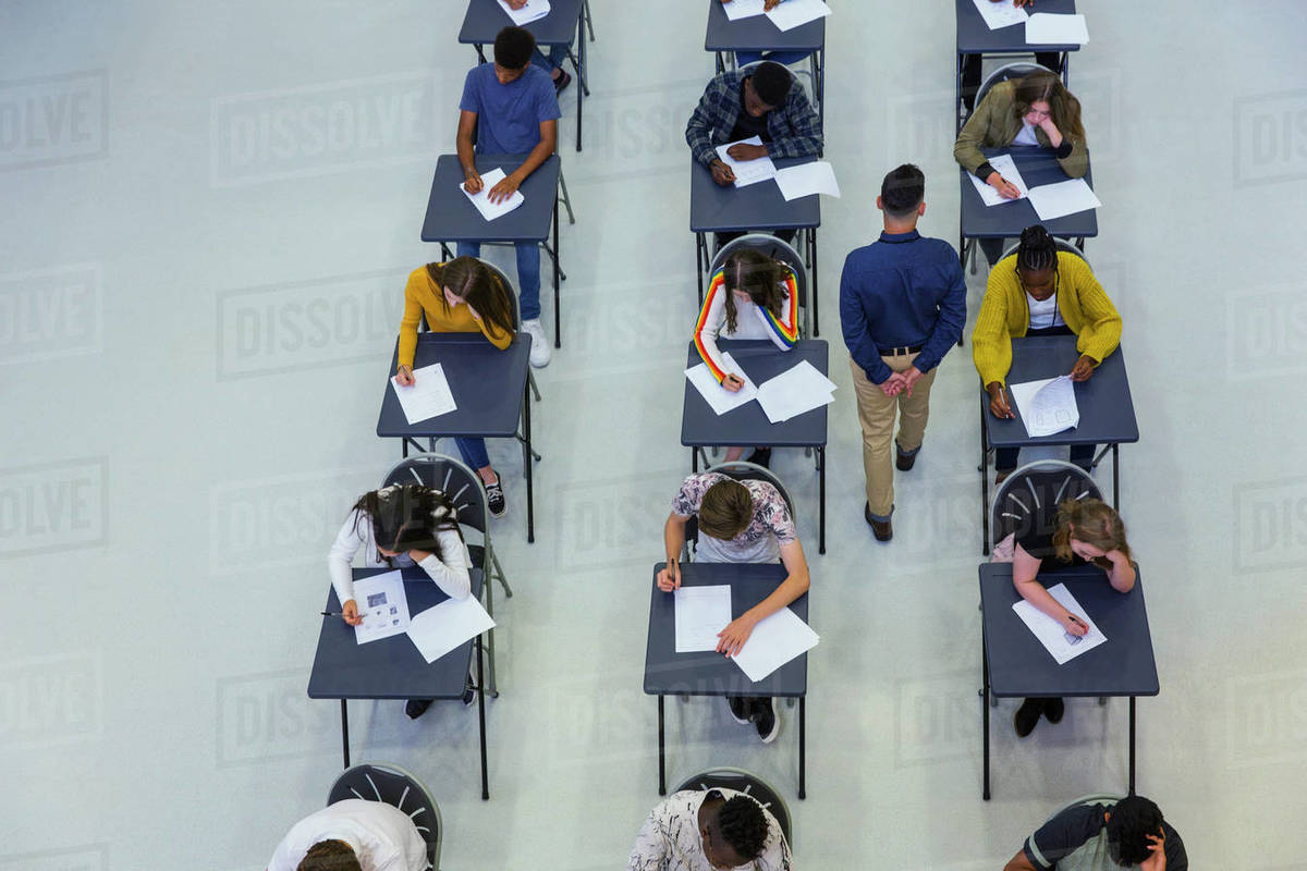 High school teacher supervising students taking exam at desks - Royalty ...