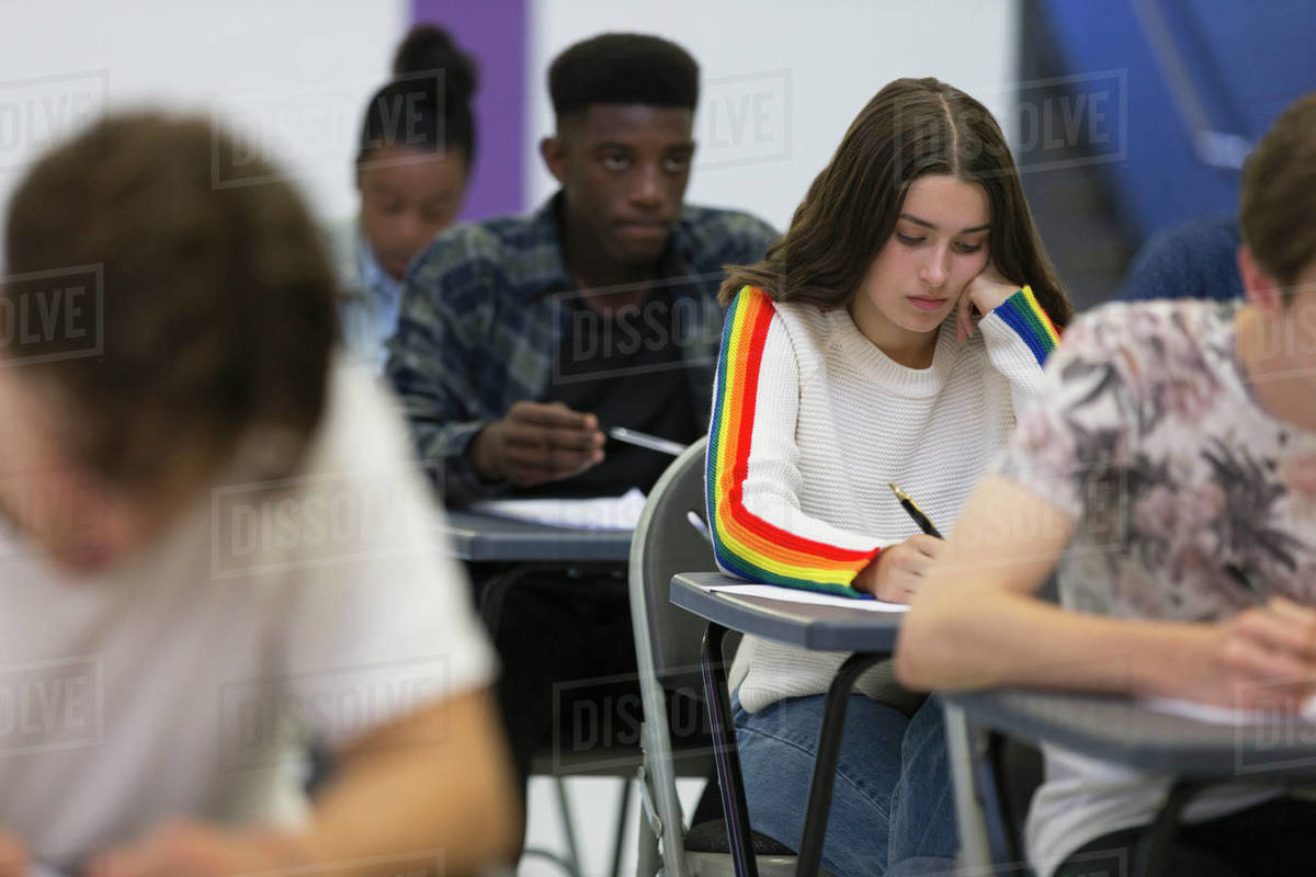 High school students taking exam at desks in classroom - Royalty-free ...