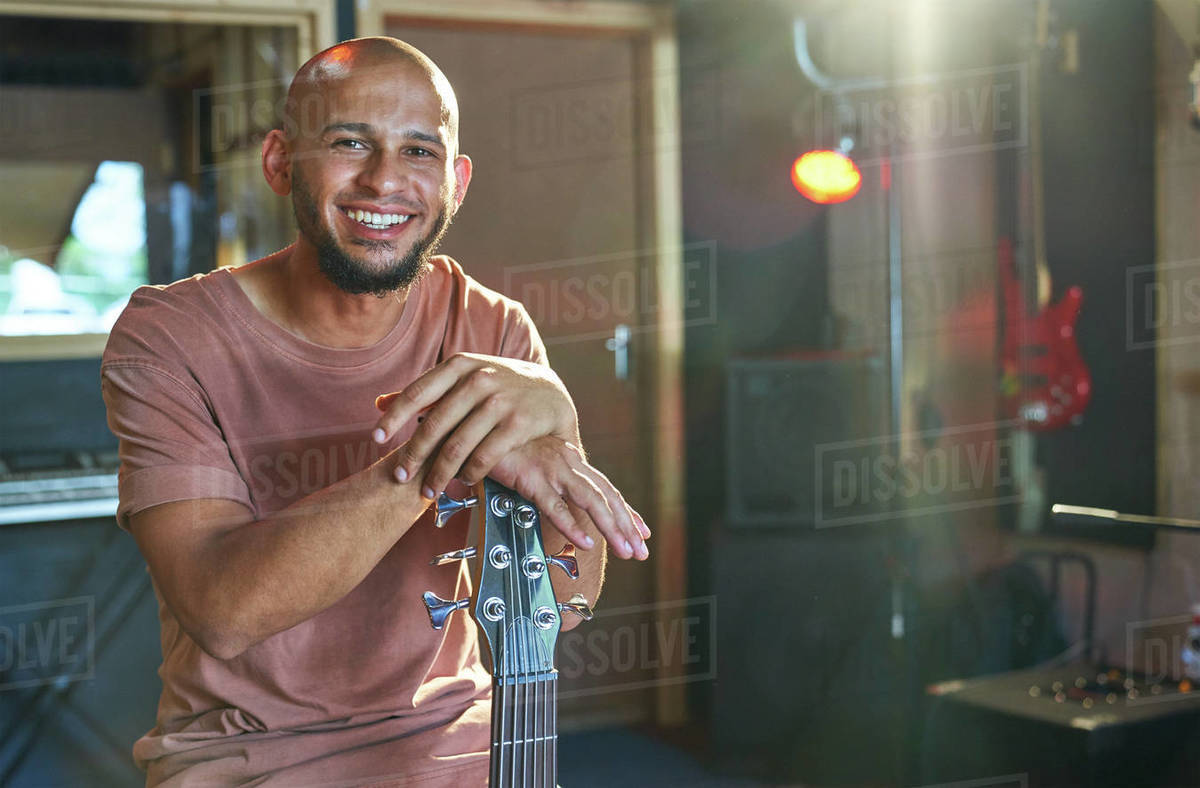 Portrait happy confident male musician with guitar in recording studio ...