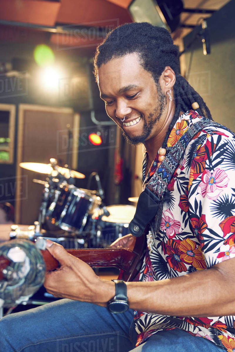 Smiling male musician playing guitar in recording studio - Royalty-free ...