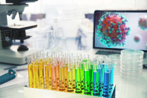Multicolor vials on laboratory table next to coronavirus on screen ...