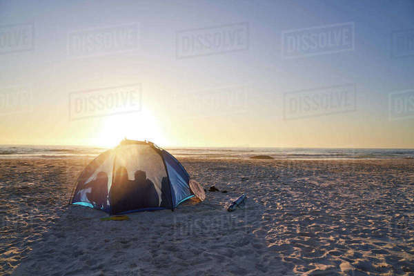 Silhouette of family inside tent on sunny beach at sunset - Royalty ...