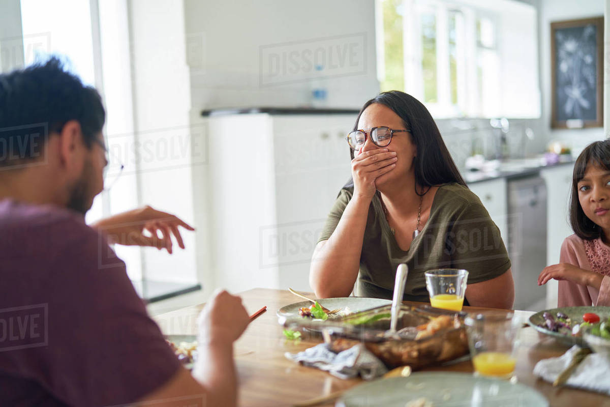 Happy family laughing at dinner table - Royalty-free Stock Photo | Dissolve
