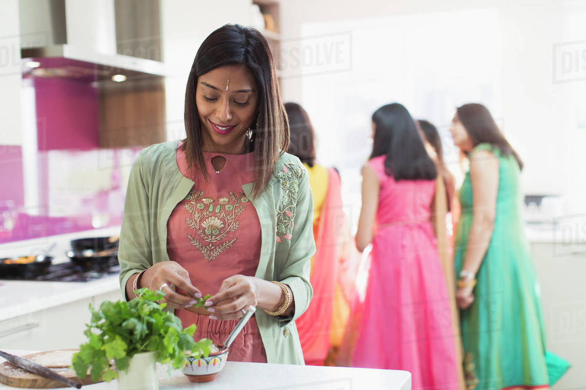 Indian woman in sari and bind cooking food with family in kitchen ...