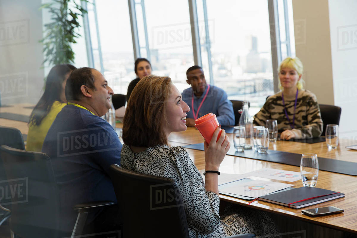 Smiling businesswoman drinking coffee in conference room meeting ...