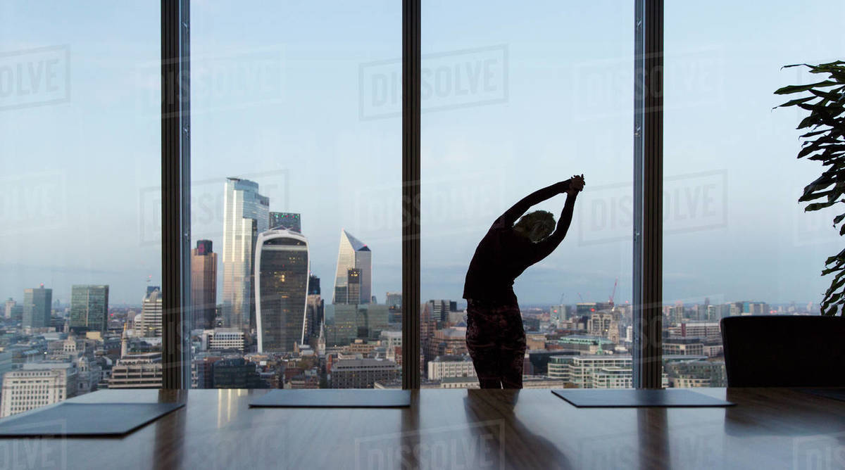 Businesswoman stretching at highrise office window, London, UK - Stock ...