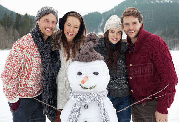 Portrait of happy friends with snowman - Royalty-free Stock Photo ...