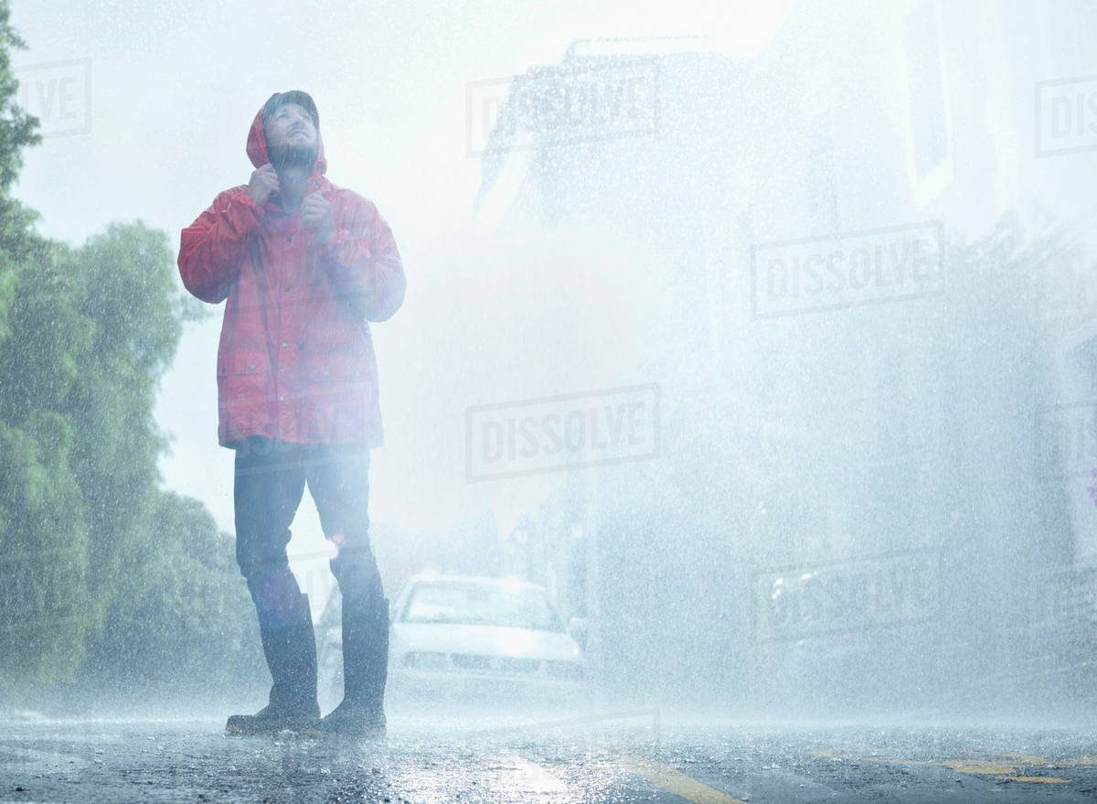 Man wearing raincoat in rainy street - Stock Photo - Dissolve