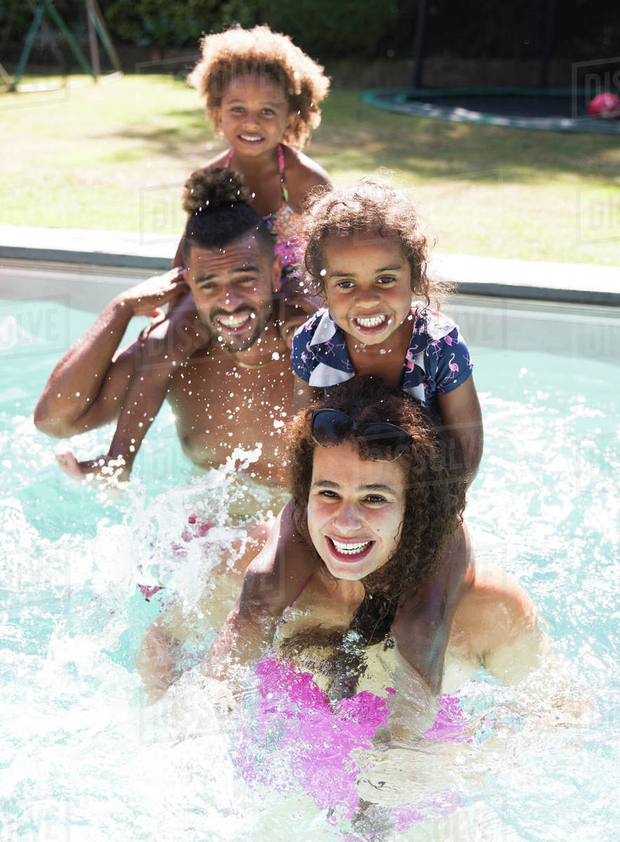 Portrait happy family splashing in sunny summer swimming pool - Royalty ...