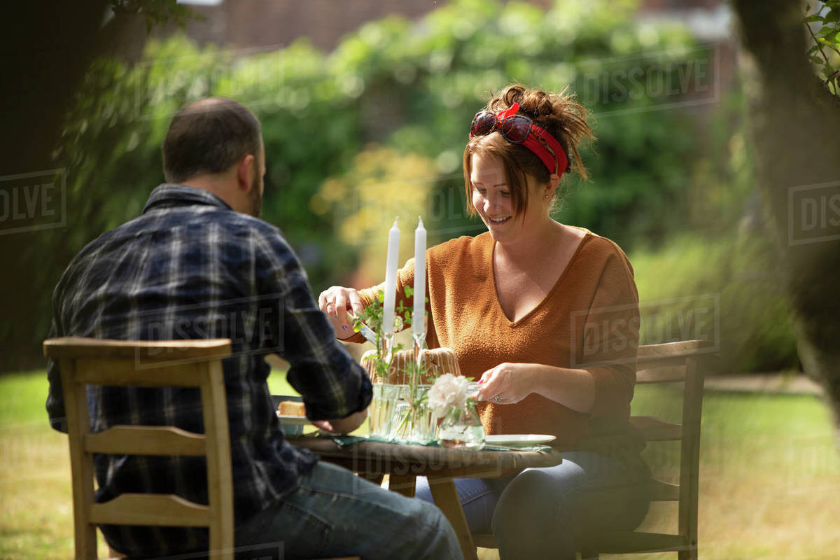 Happy couple enjoying cake at table in summer garden - Royalty-free ...