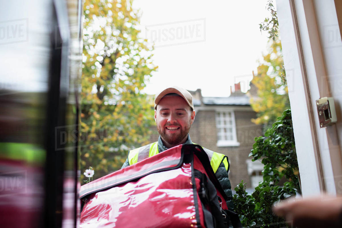 Friendly delivery man delivering food at front door - Royalty-free ...