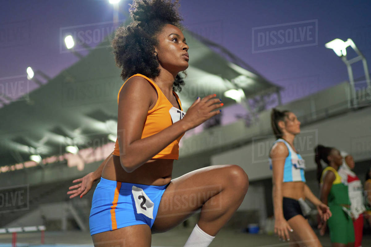 Focused female track and field athlete preparing for race in stadium ...