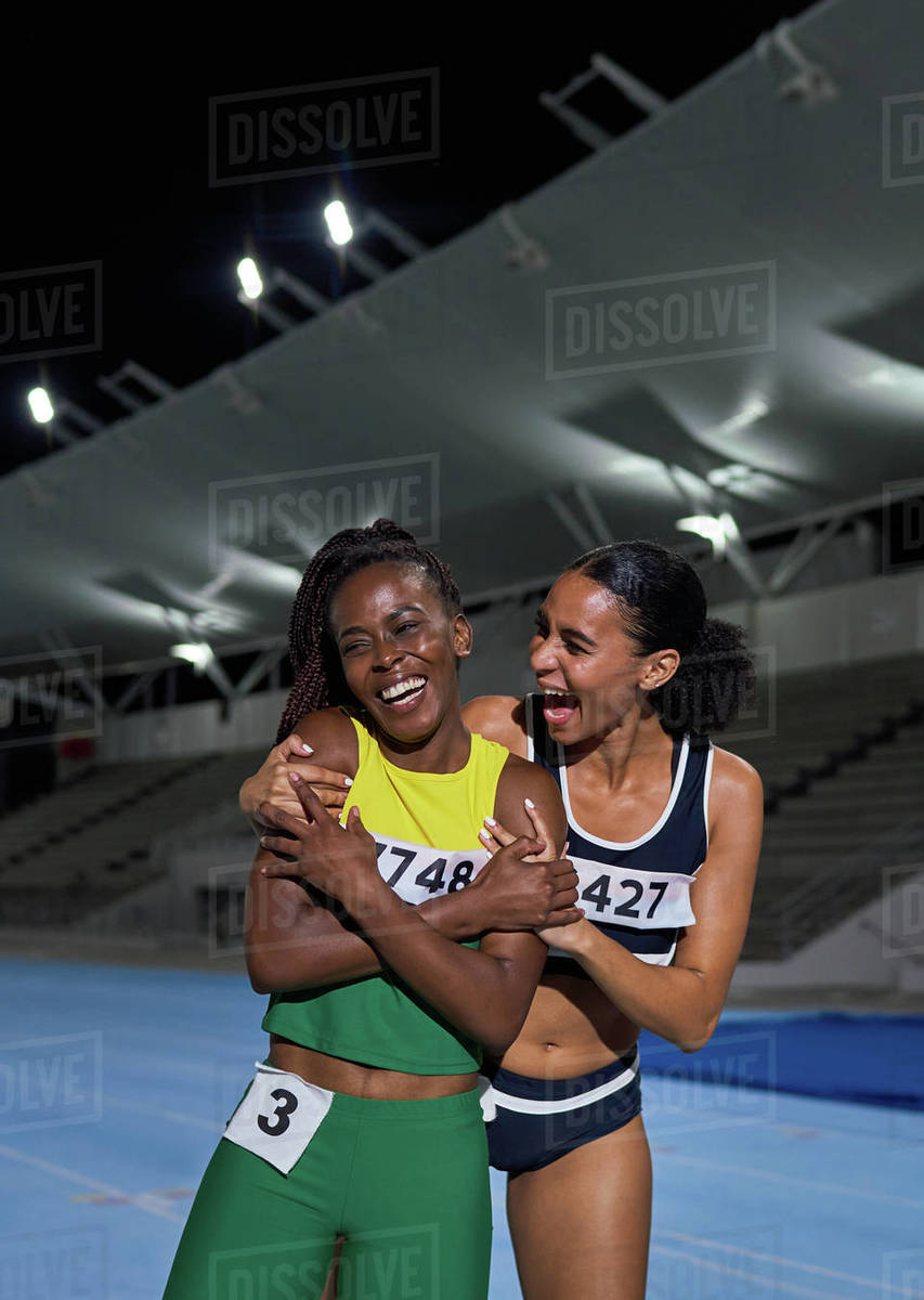 Happy female track and field athletes hugging after competition ...