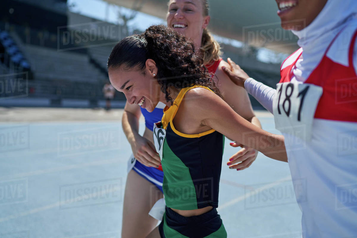 Happy female track and field athletes celebrating on track - Royalty ...