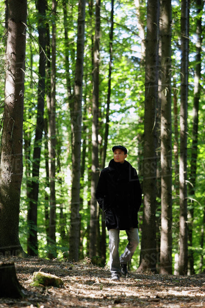 Young man walking in forest - Royalty-free Stock Photo | Dissolve