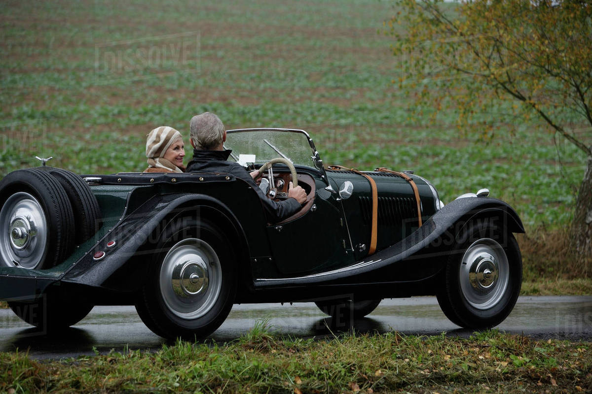 Senior couple driving in antique car on country road - Royalty-free ...
