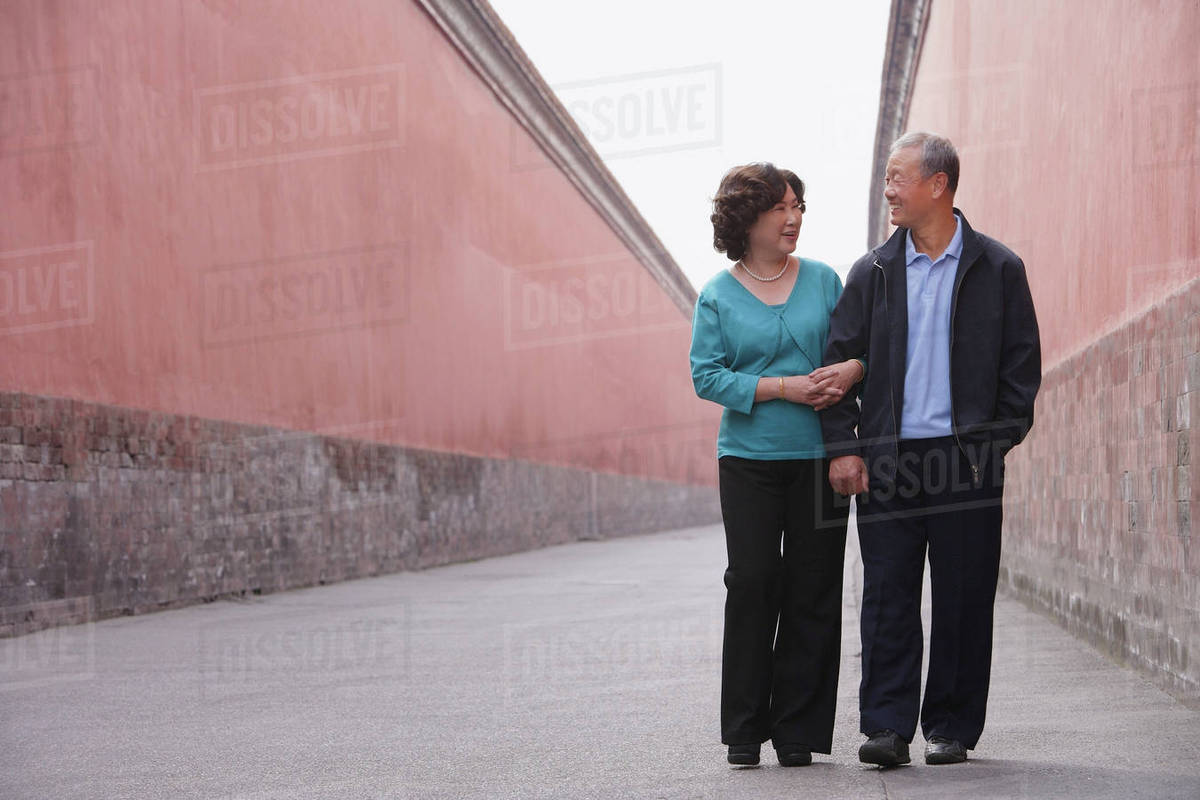 A man and woman link arms as they walk together - Royalty-free Stock ...