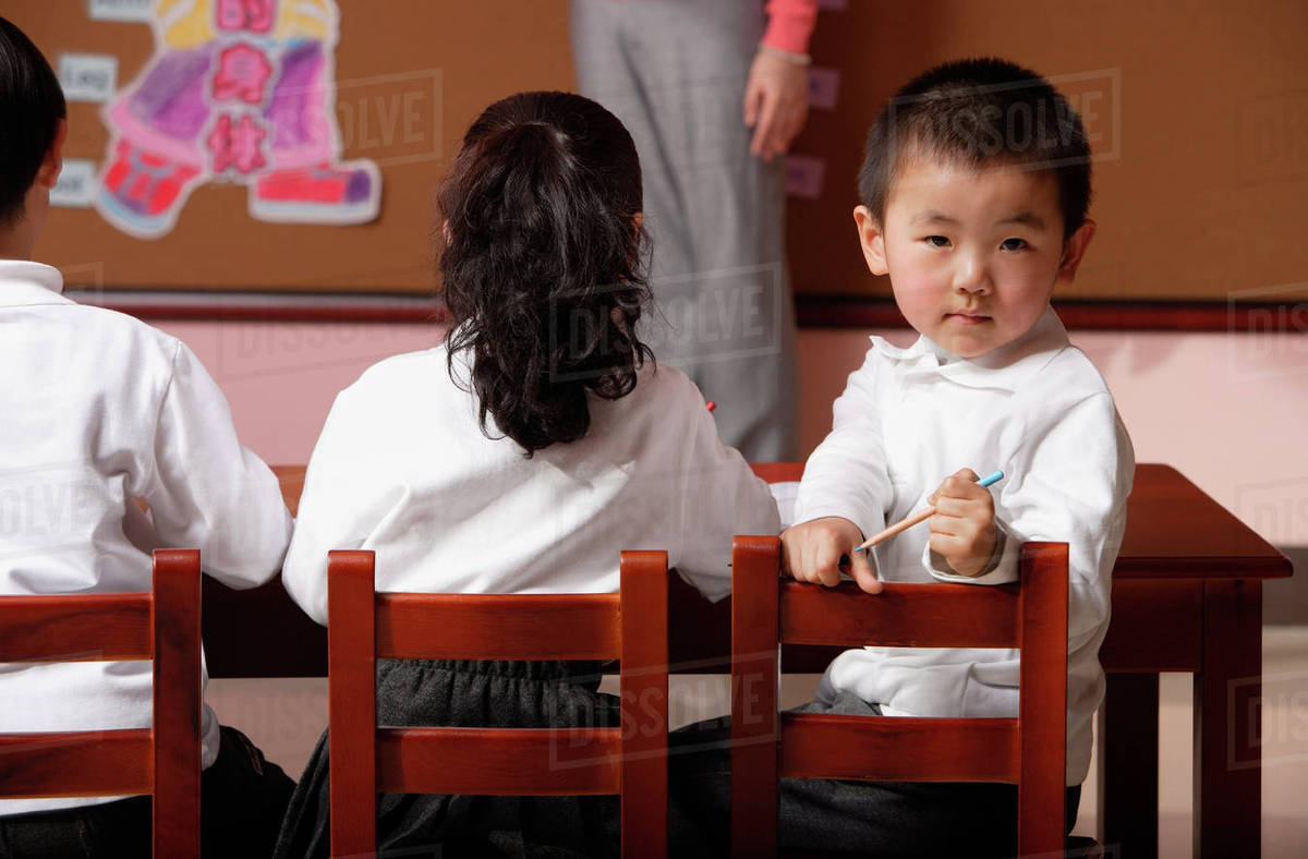 Students in class with teacher, schoolboy turning head around looking ...