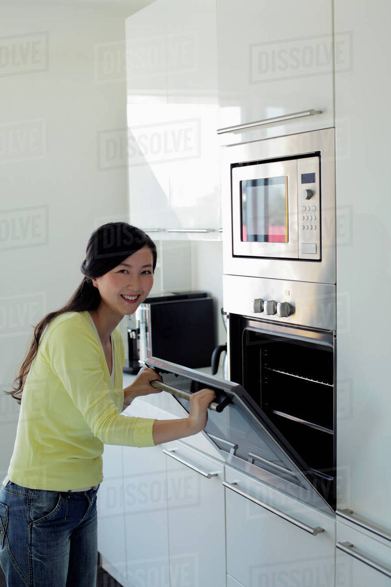 Young woman opening oven door and smiling - Royalty-free Stock Photo ...