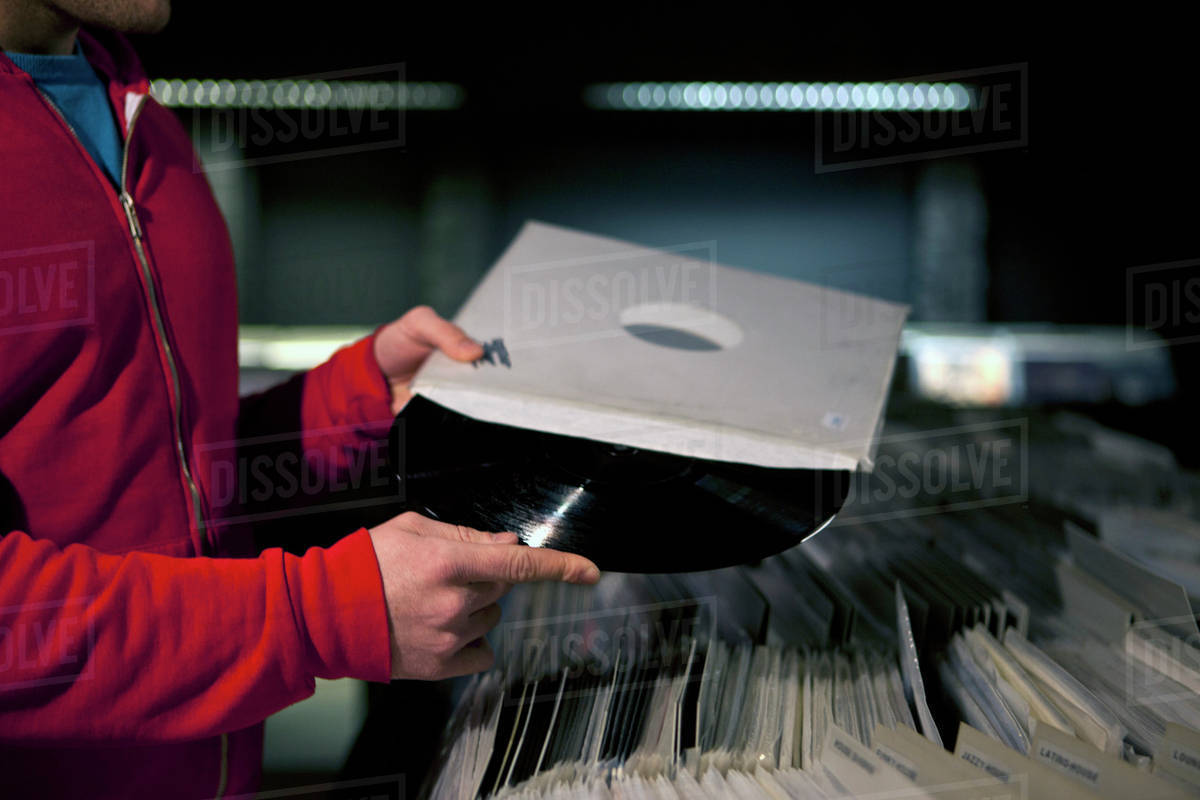 A man taking a record out of its sleeve in a record store - Royalty ...