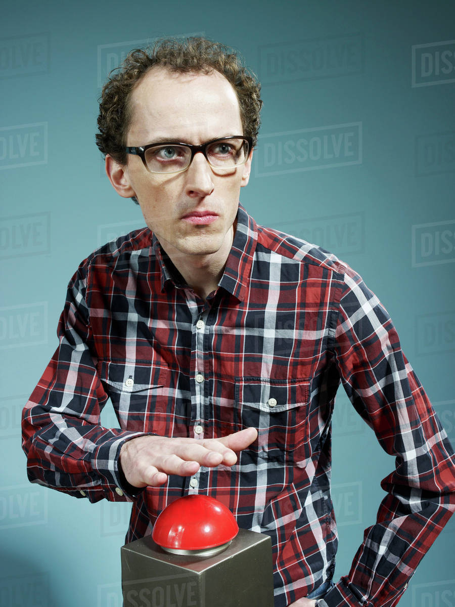 A nerdy guy with his hand poised above a red game show buzzer - Royalty ...