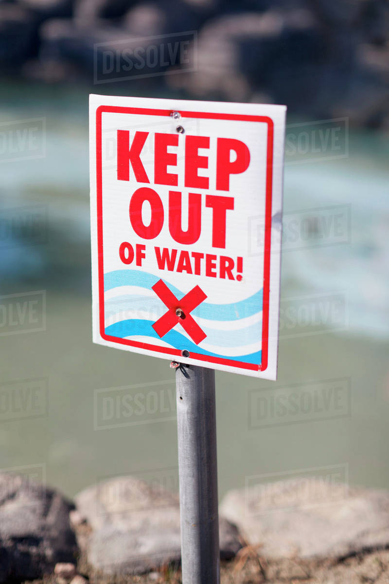A Keep Out of Water sign posted on a rocky beach - Stock Photo - Dissolve