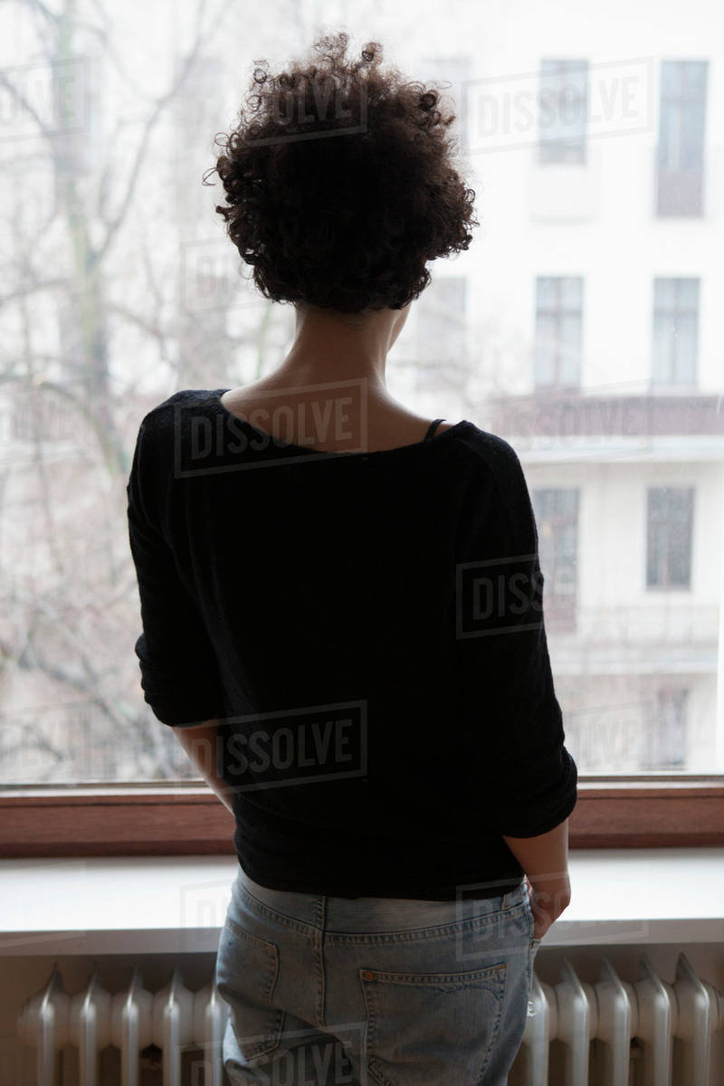 Rear view of a woman looking through a window - Royalty-free Stock ...