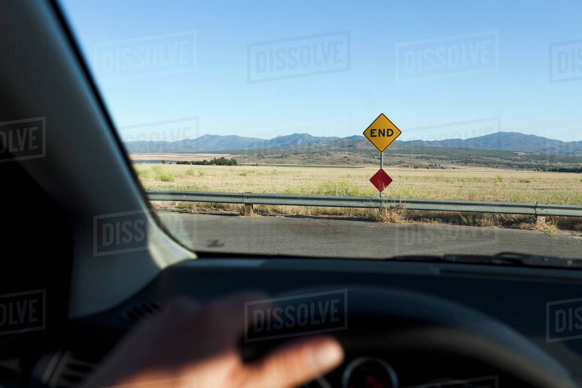 View through a car windshield of an END road sign and mountain ranges ...