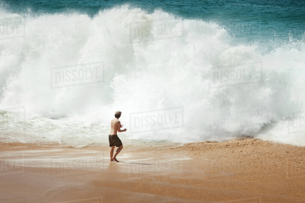 Man facing big wave on beach in La Graciosa, Canary Islands, Spain ...