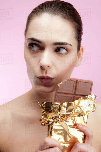 A young woman holding a large chocolate bar looking guilty - Stock ...