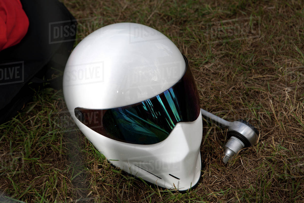 A sleek modern crash helmet lying on grass next to socket wrench ...
