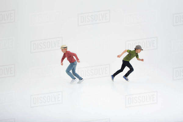 Two boys running opposite direction against white background - Stock ...