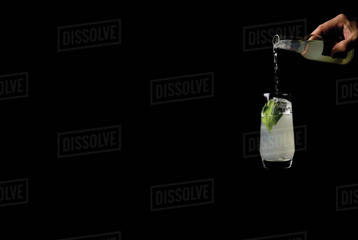 Hand pouring cocktail in glass over black background - Stock Photo ...