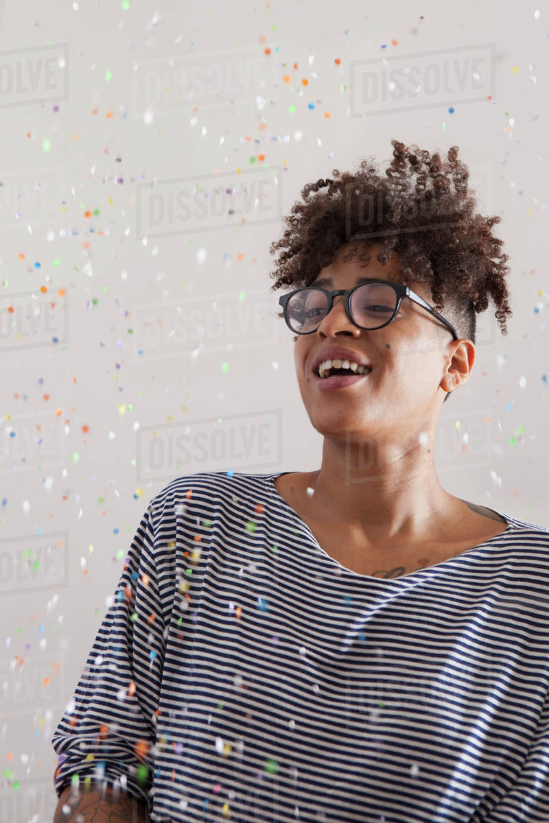 Happy young woman looking at confetti flying at home - Royalty-free ...