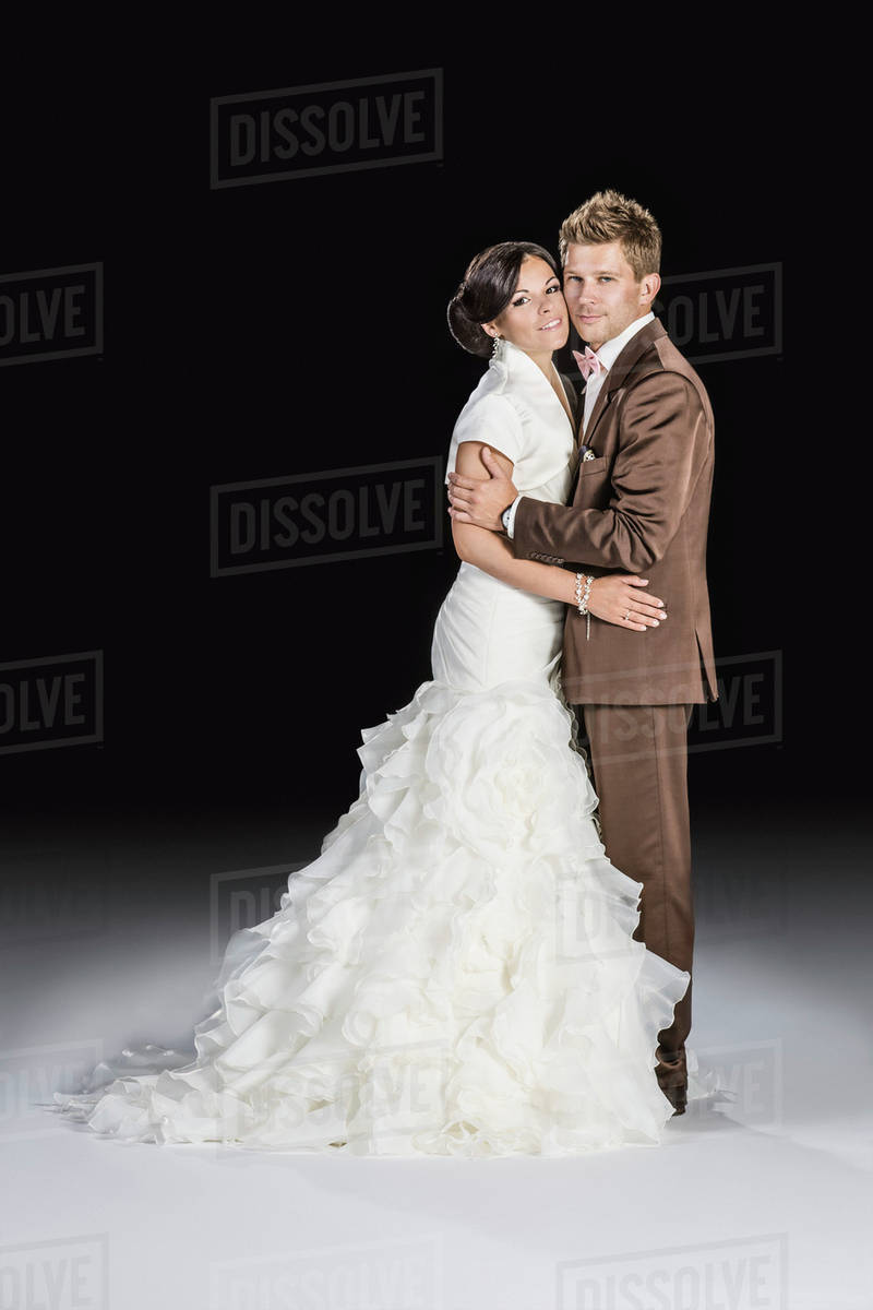 Full length side view of bride and groom standing against black ...